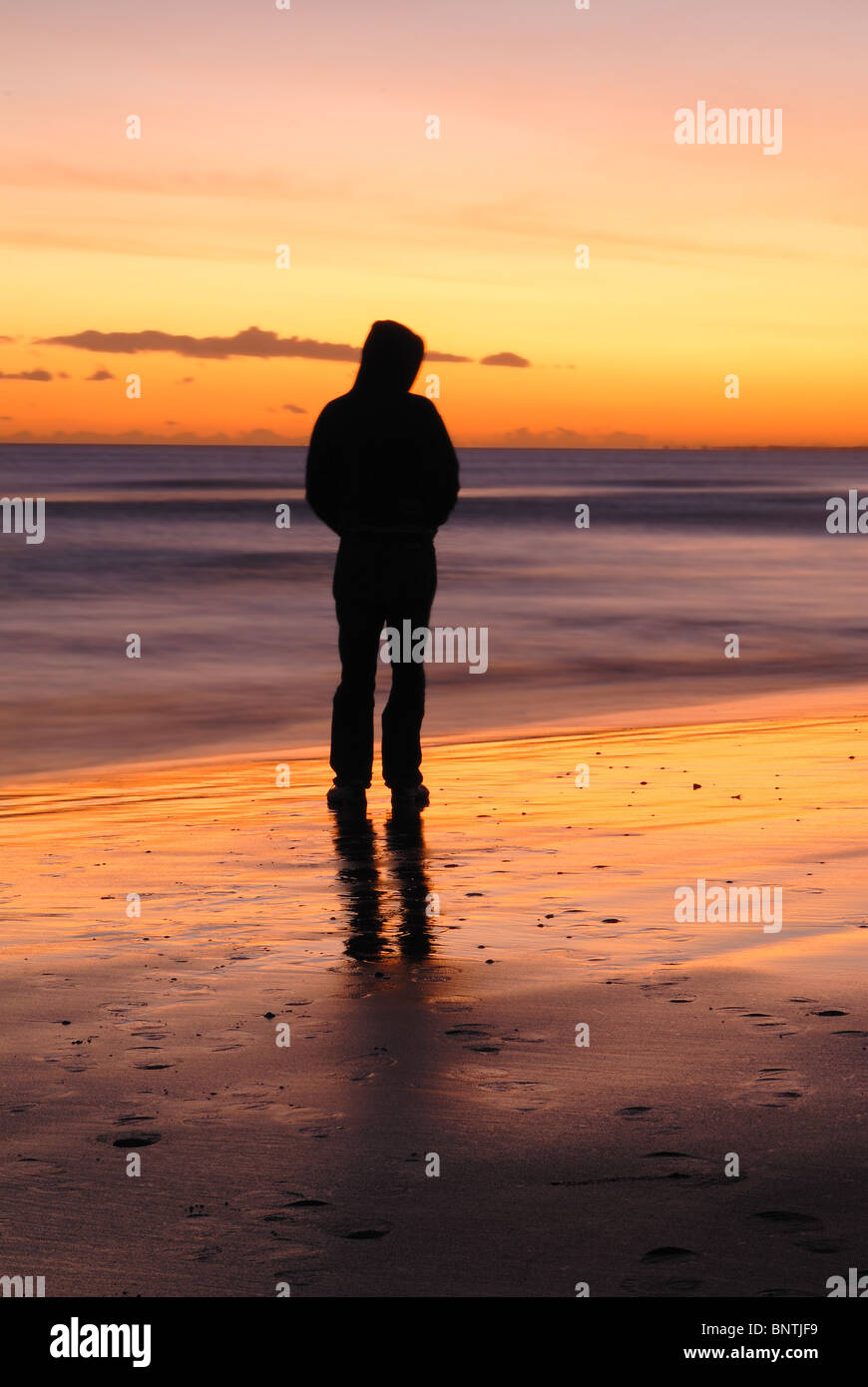 One man alone thinking looking out to the sea whilst the sun is setting ...