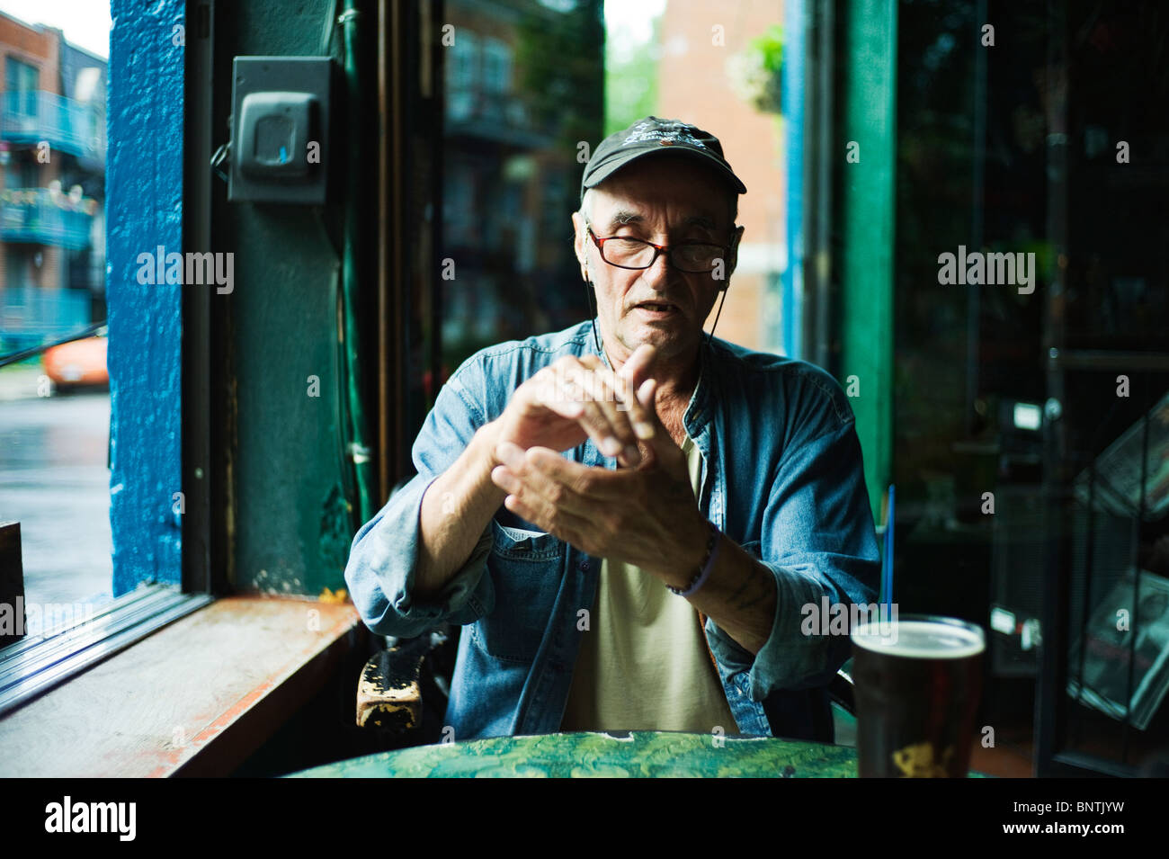 Old man gestures while sitting at bar table Stock Photo - Alamy