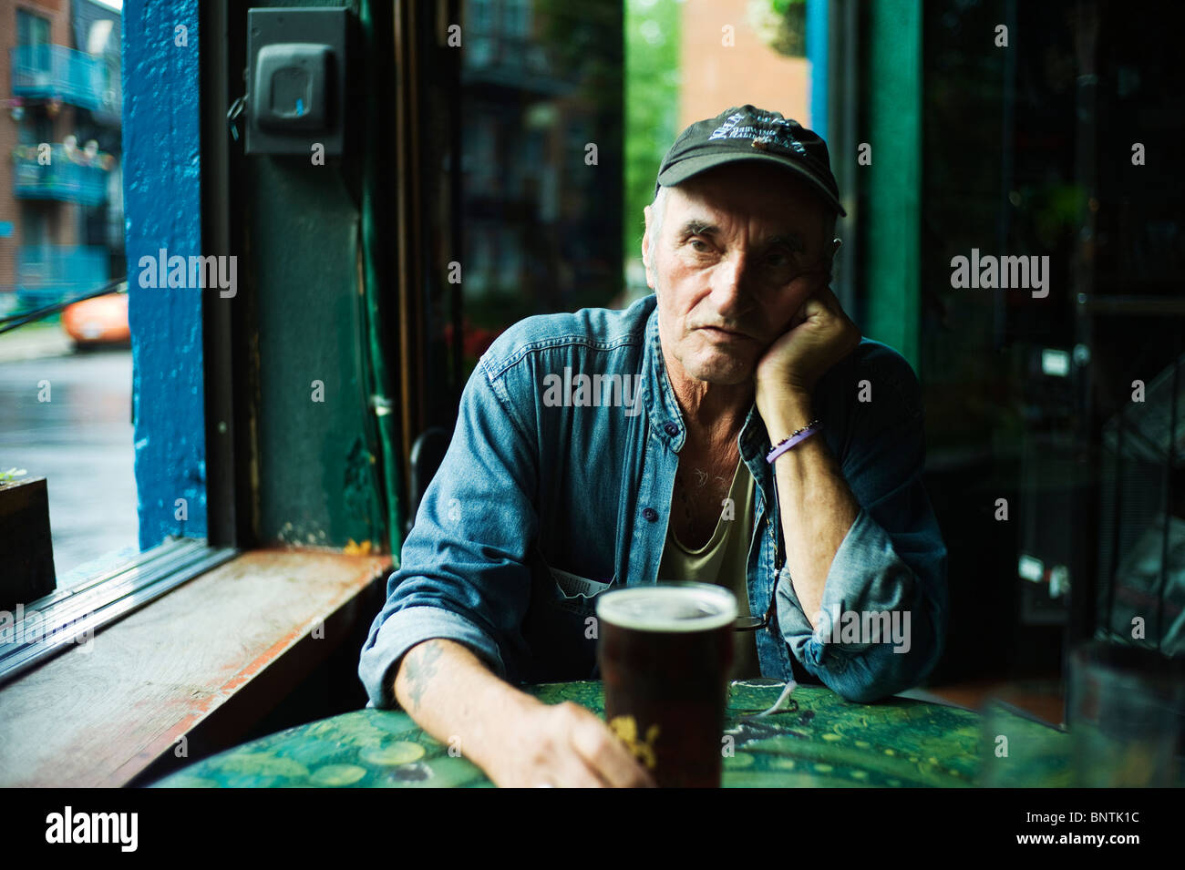 Old man rests head on hand at bar table Stock Photo - Alamy