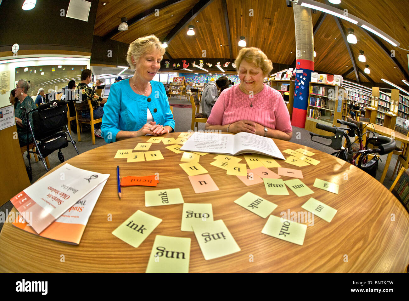 A volunteer reading instructor teaches reading to an elderly Hispanic ...