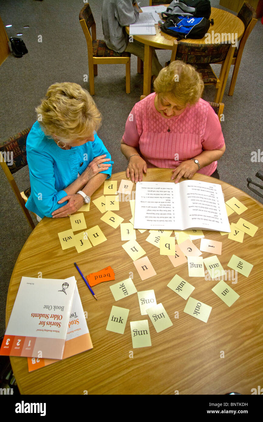 A volunteer reading instructor teaches reading to an elderly Hispanic ...