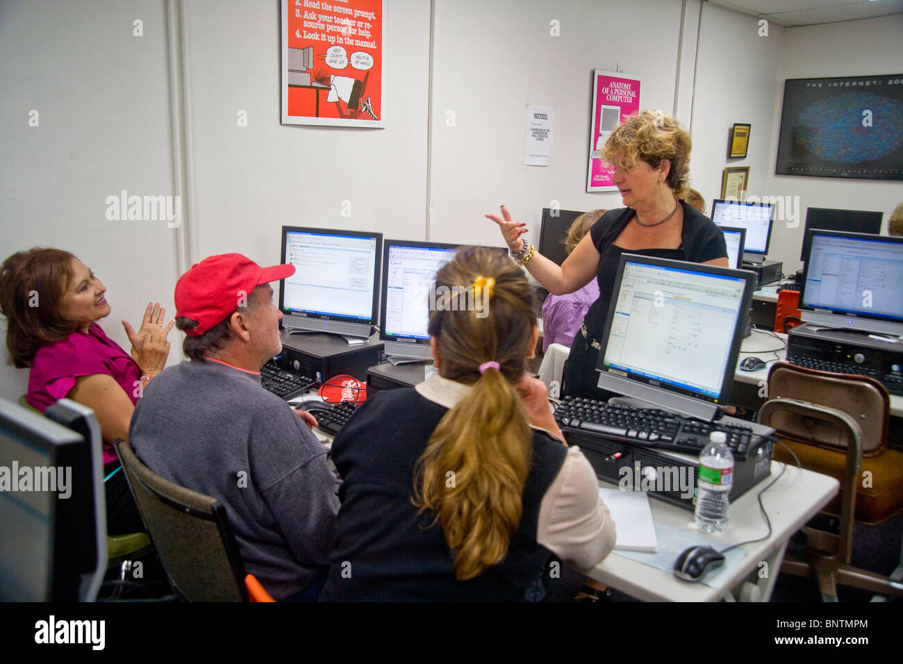 A Hispanic adult education teacher conducts a computer class for ...