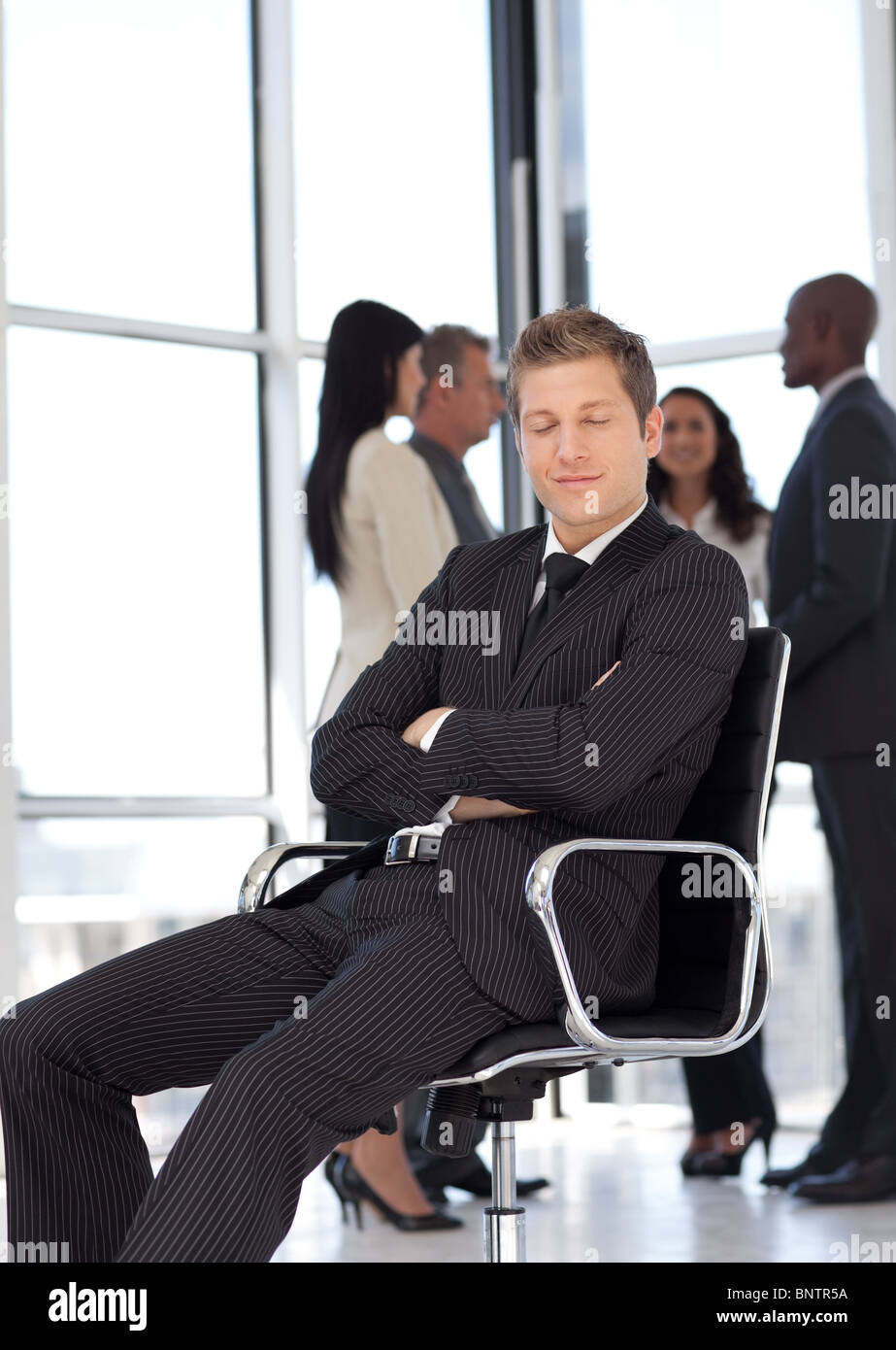 manager relaxing in office with team in background Stock Photo - Alamy