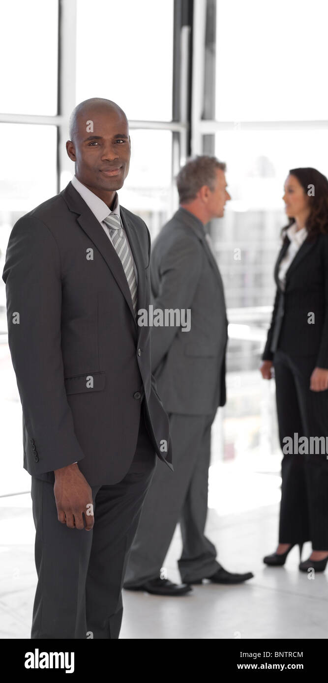 Serious business leader looking at camera in front of team Stock Photo ...