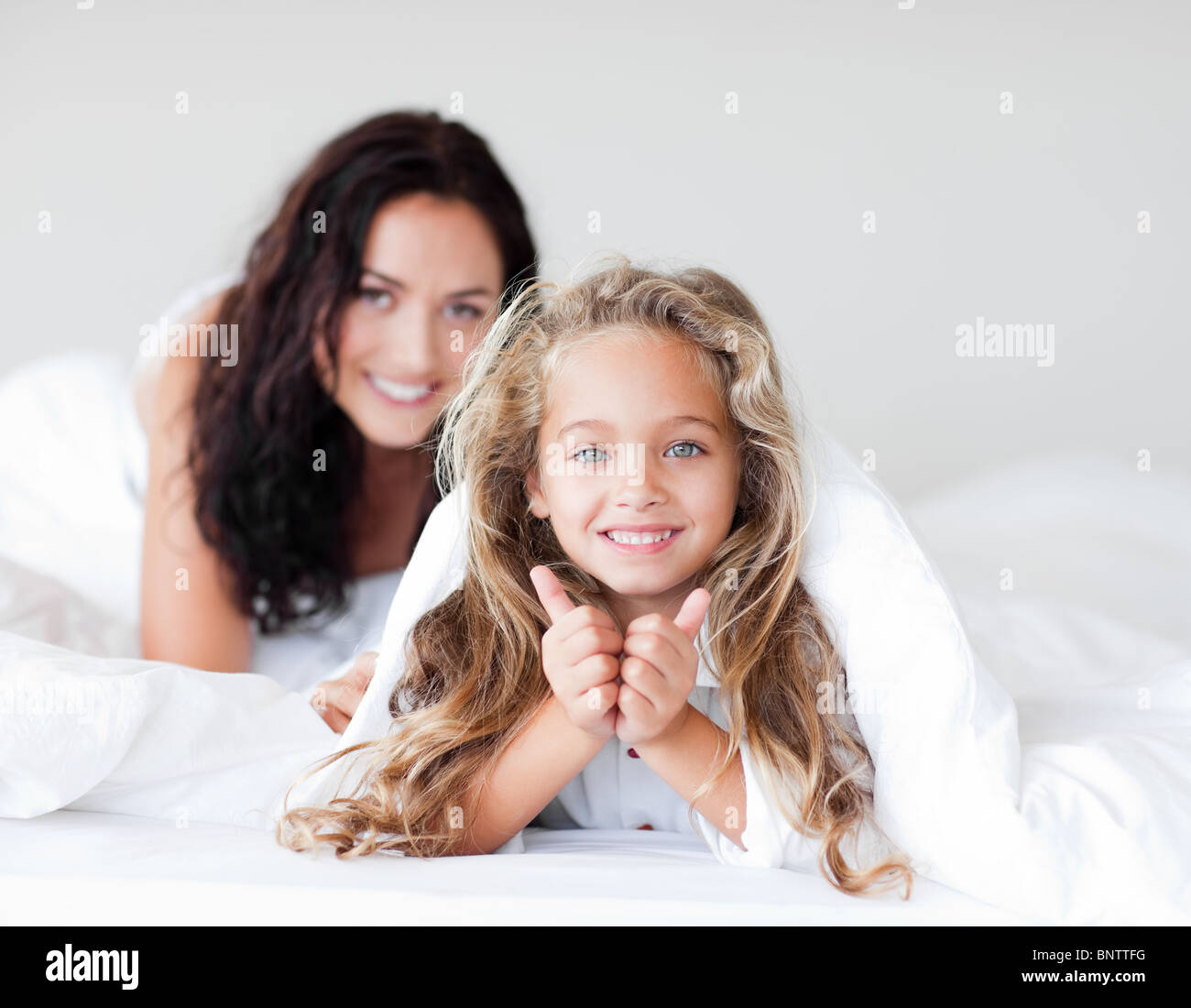 Attractive mother and daugther embracing on bed Stock Photo - Alamy