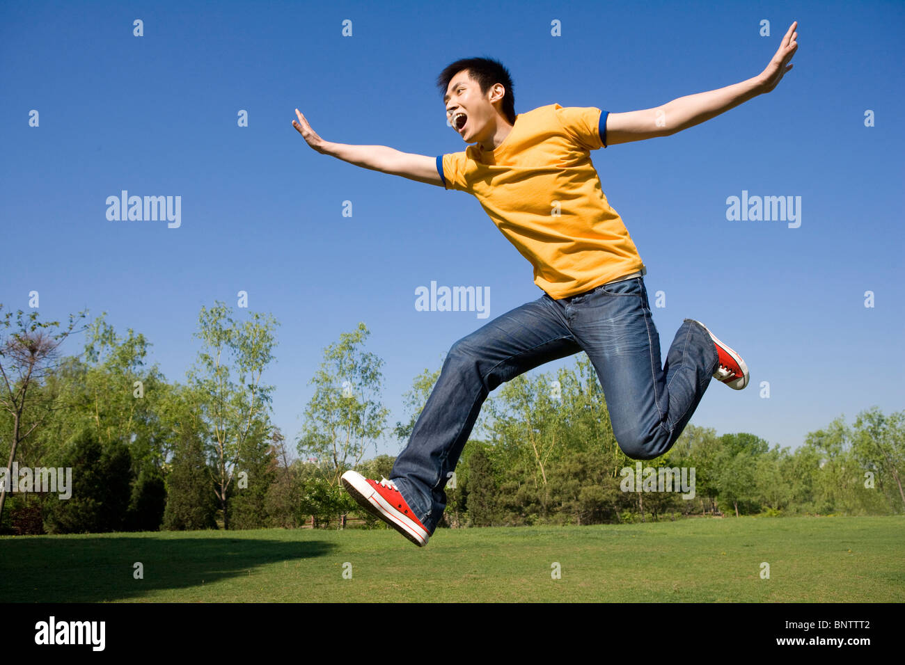 Young man jumping in air at park Stock Photo - Alamy