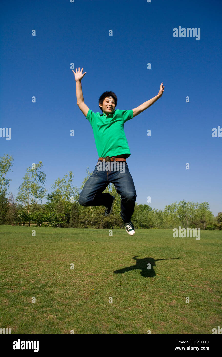 Young man jumping in air at park Stock Photo - Alamy