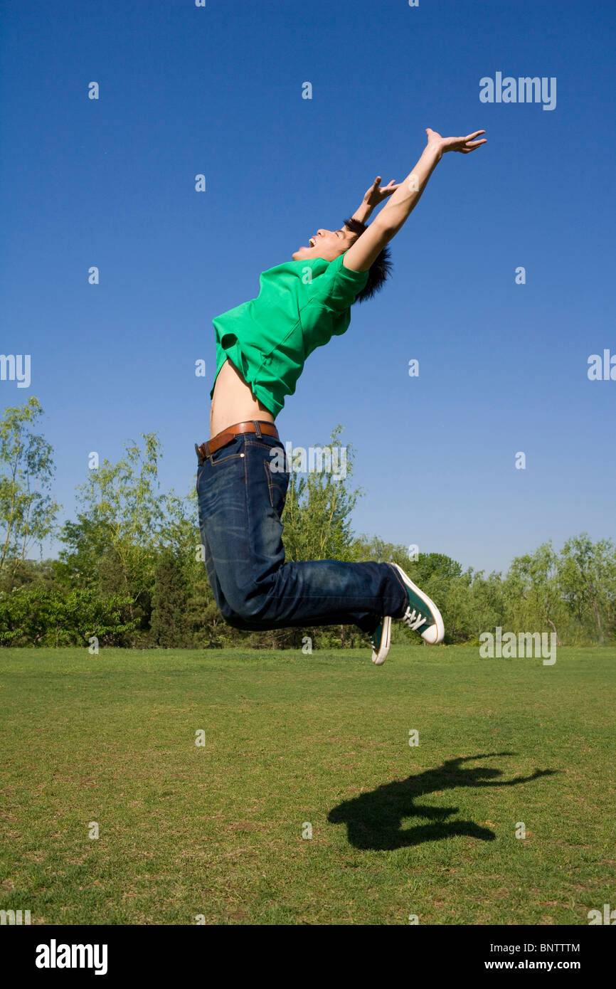 Young man jumping in air at park Stock Photo - Alamy