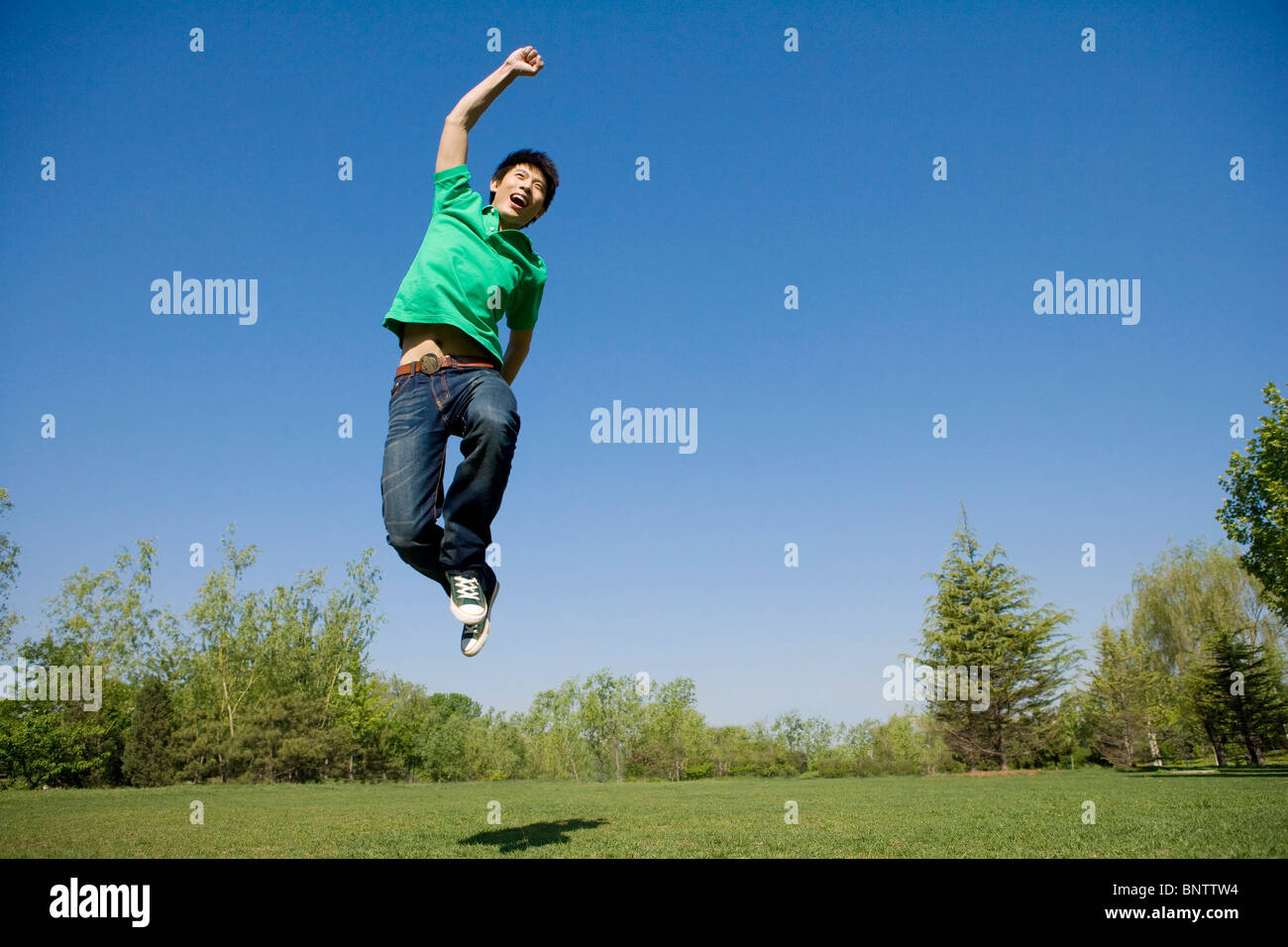 Young man jumping in air at park Stock Photo - Alamy