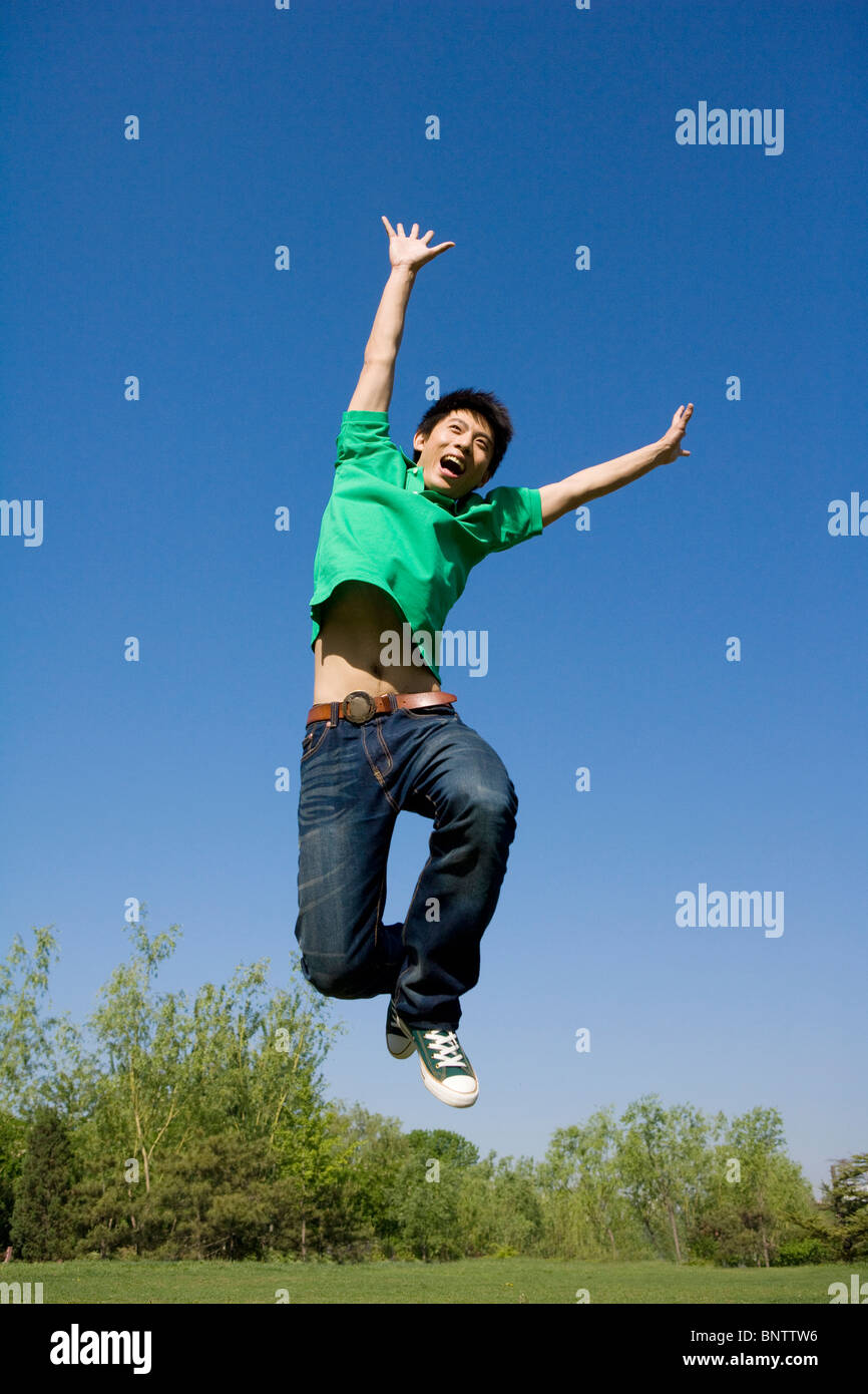Young man jumping in air at park Stock Photo - Alamy