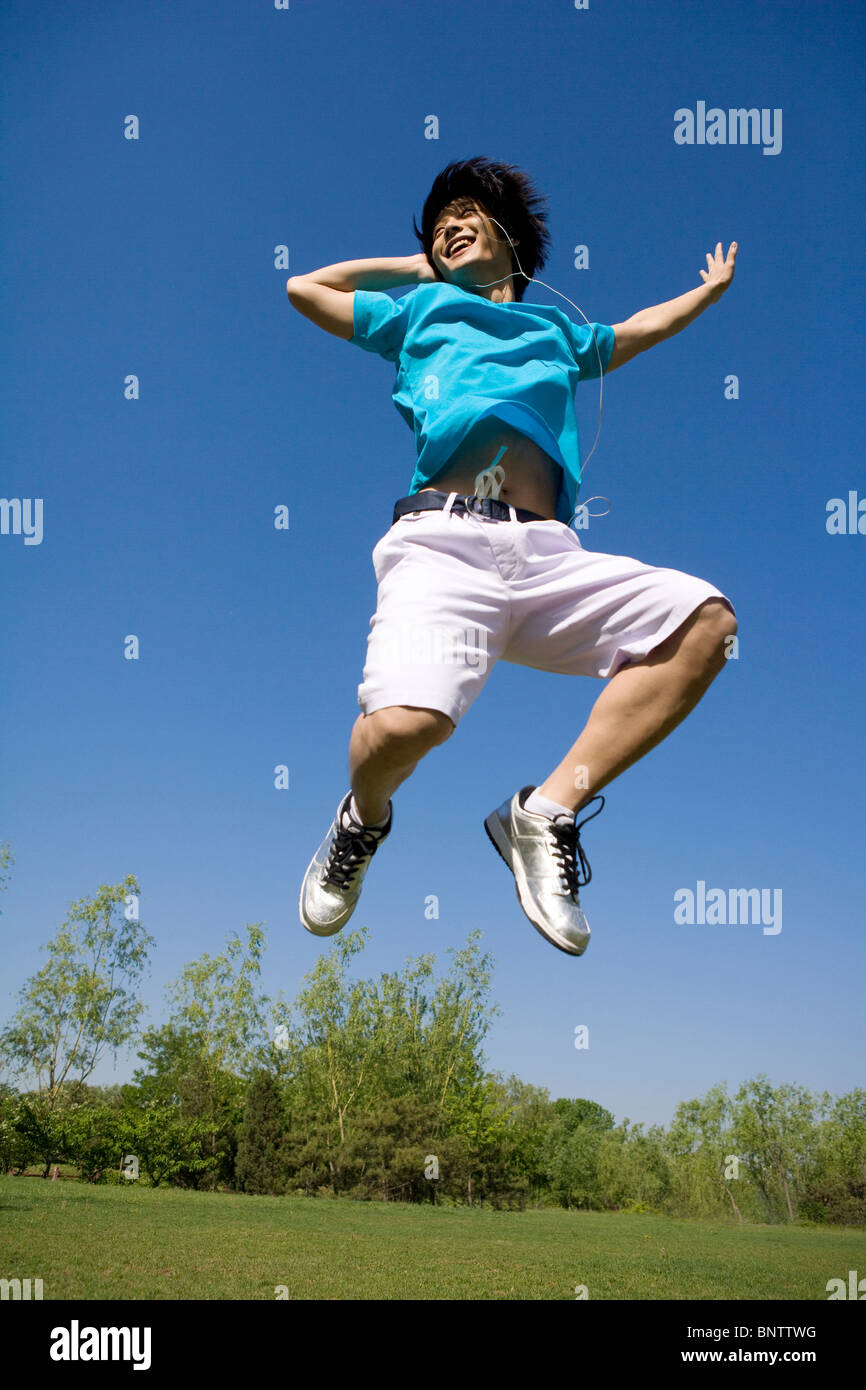 Young man jumping in air at park Stock Photo - Alamy