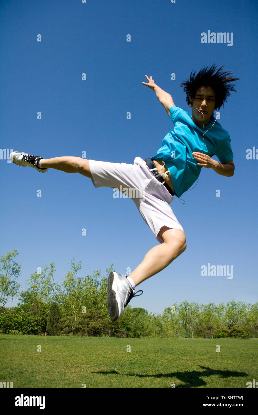 Young man jumping in air at park Stock Photo - Alamy