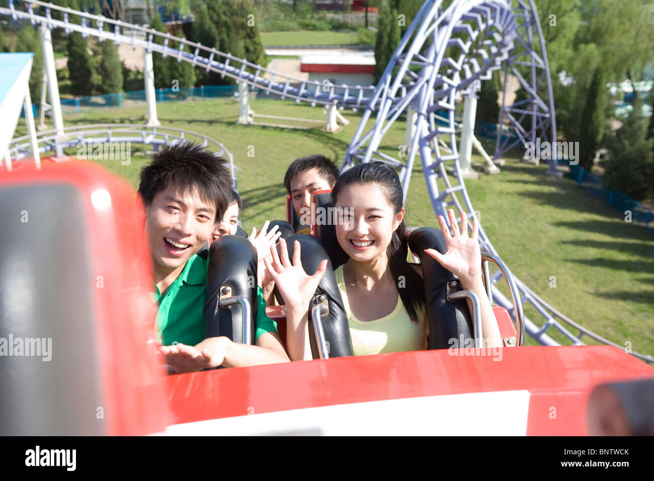 Young people riding a rollercoaster Stock Photo - Alamy