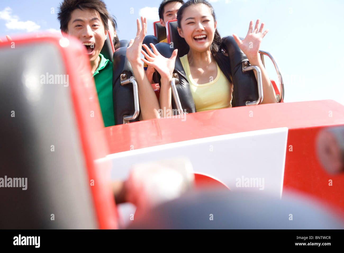 Young people riding a rollercoaster Stock Photo - Alamy