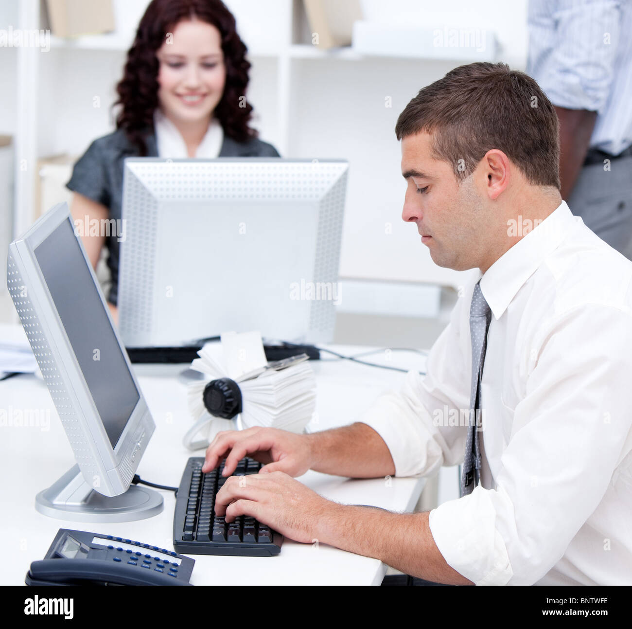Assertive young business people working at computers Stock Photo - Alamy