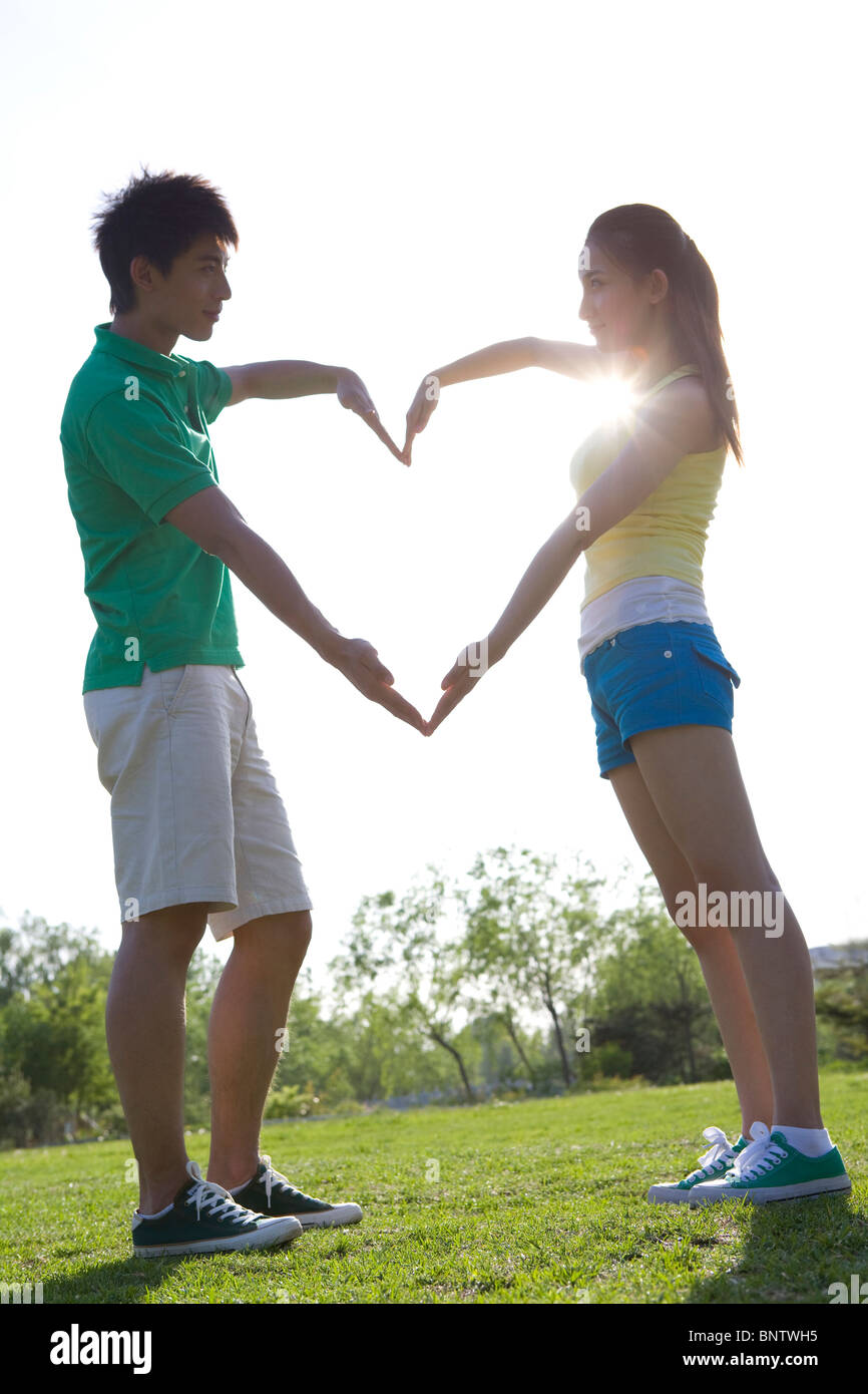 A young couple making a heart shape with their arms Stock Photo - Alamy