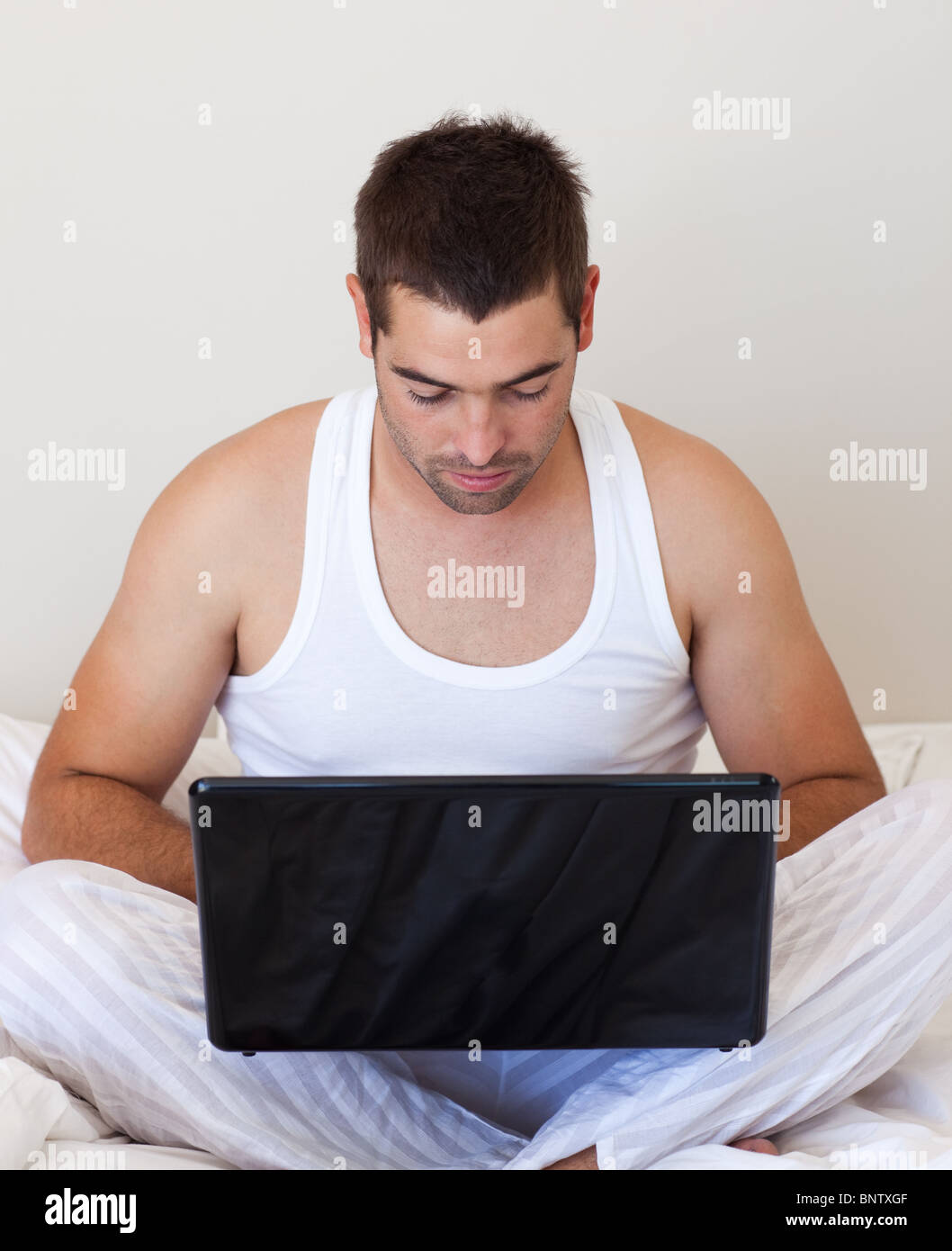 Handsome man using a laptop in his bedroom Stock Photo - Alamy