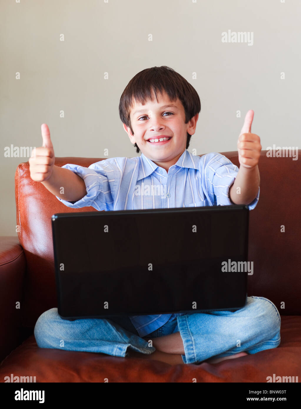 Child playing with his laptop with thumbs up Stock Photo - Alamy