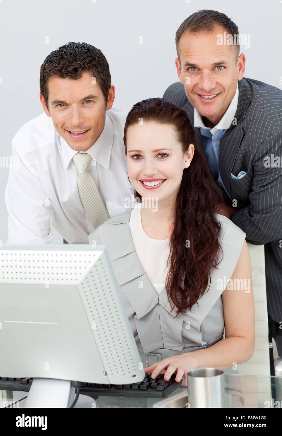Smiling three business people using a computer Stock Photo - Alamy