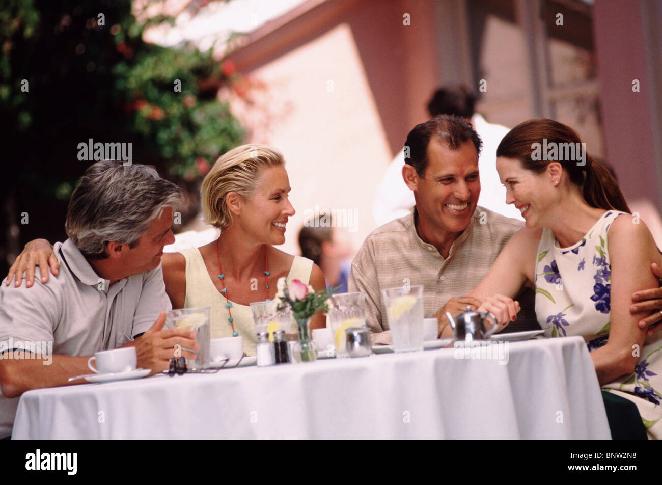 Two couples having dinner on the patio of a restaurant Stock Photo - Alamy