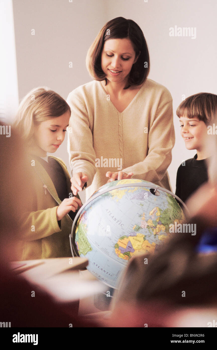 Elementary school teacher showing globe to students Stock Photo - Alamy