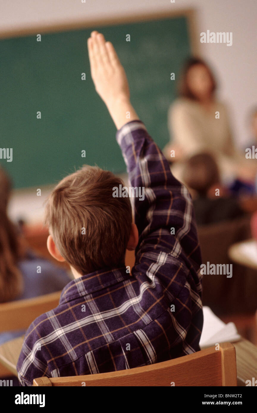 Child raising his hand in school classroom Stock Photo - Alamy