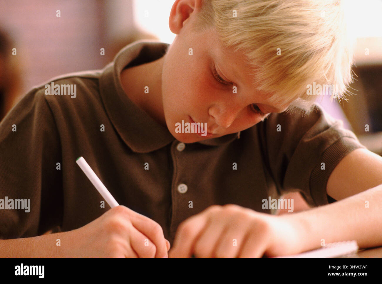 Elementary school student writing at his desk Stock Photo - Alamy