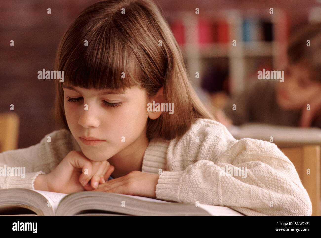 Elementary school student reading book at her desk Stock Photo - Alamy