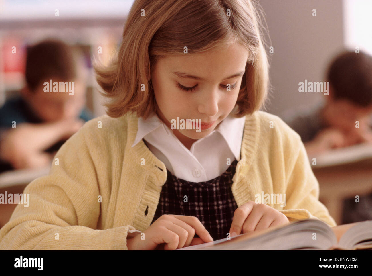 Elementary school student reading book at her desk Stock Photo - Alamy
