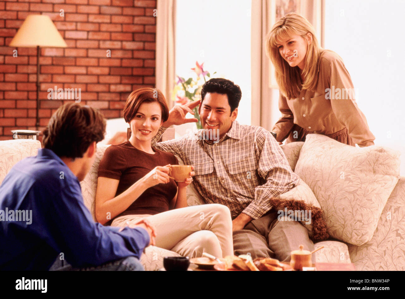 Four friends socializing in living room Stock Photo - Alamy