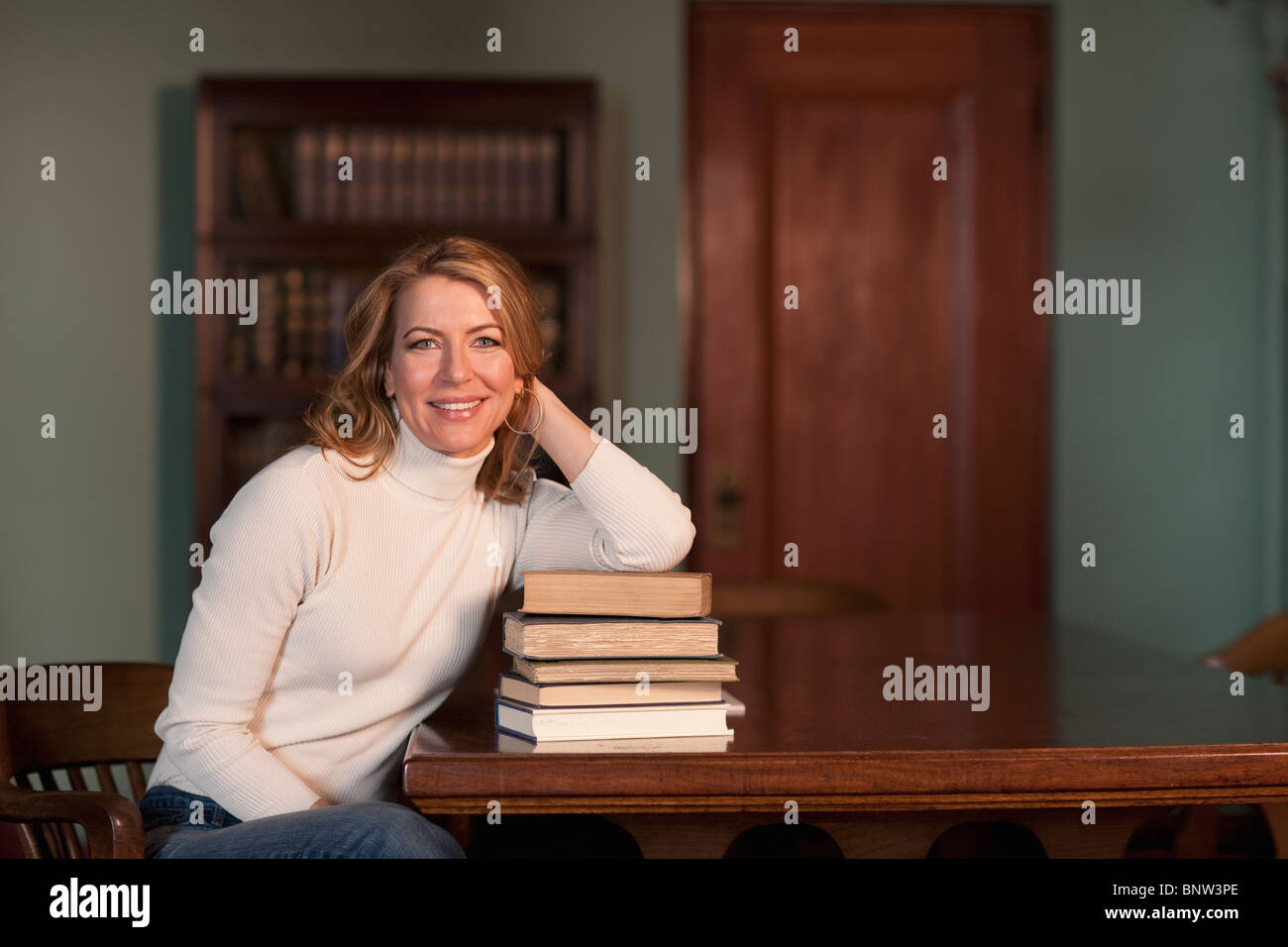 Woman leaning on stack of books Stock Photo - Alamy