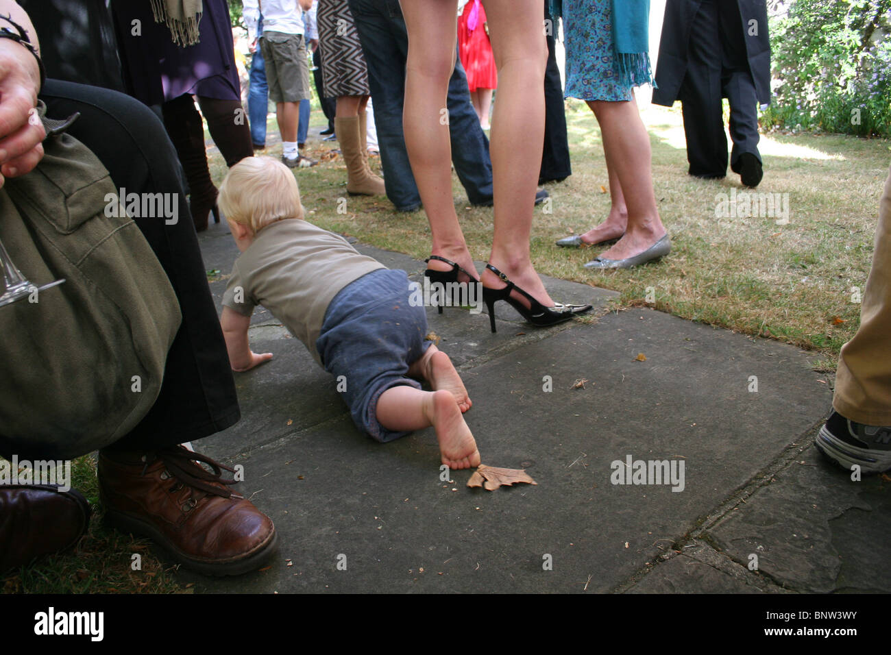 Baby crawling through a crowd at a garden party, London, UK Stock Photo ...