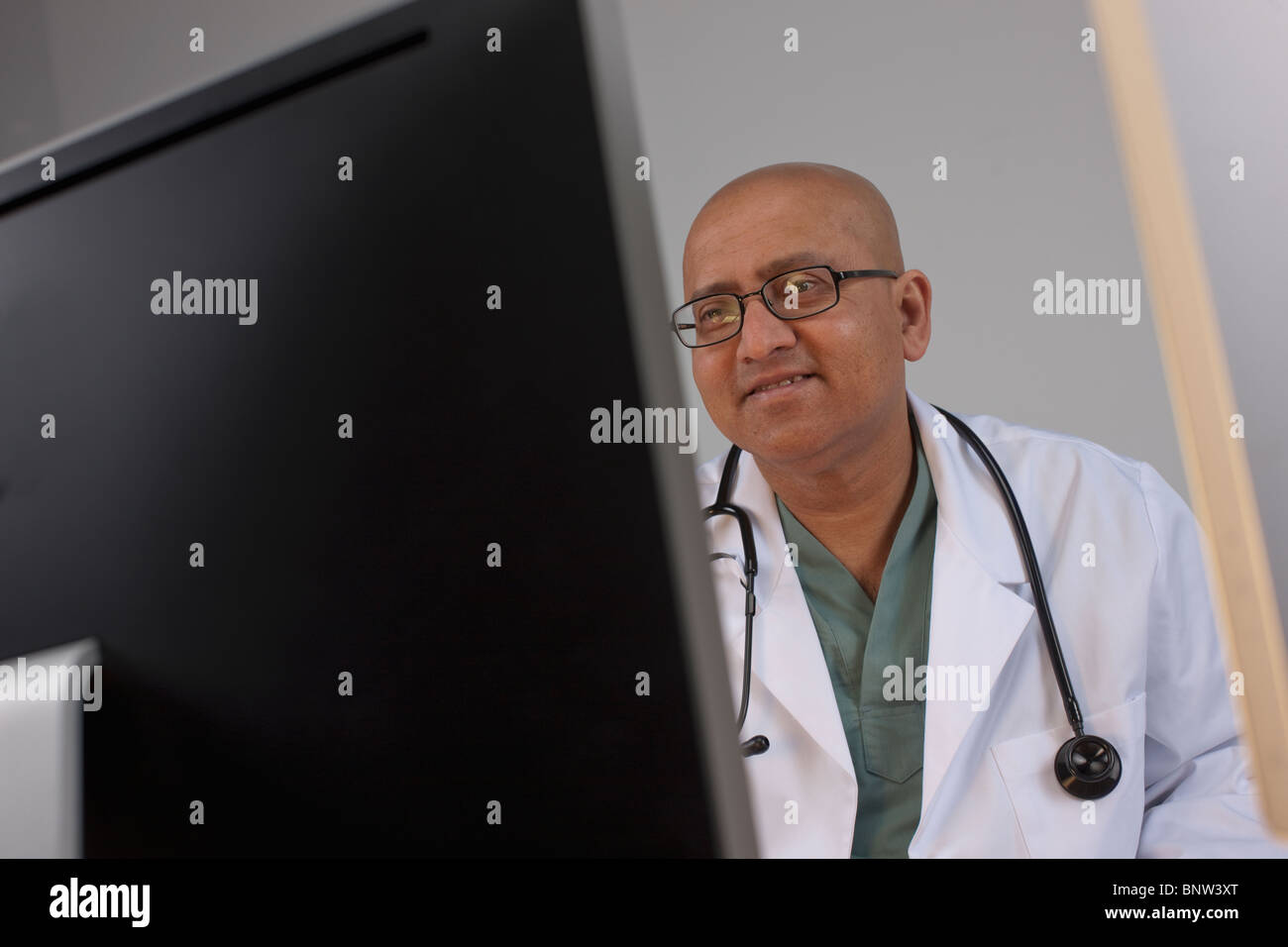 Doctor looking at computer monitor Stock Photo - Alamy