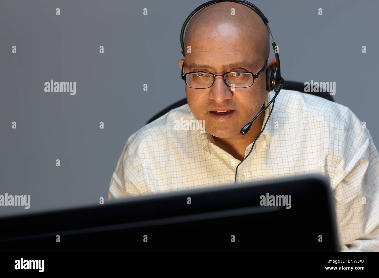 Man wearing headset working on computer Stock Photo - Alamy
