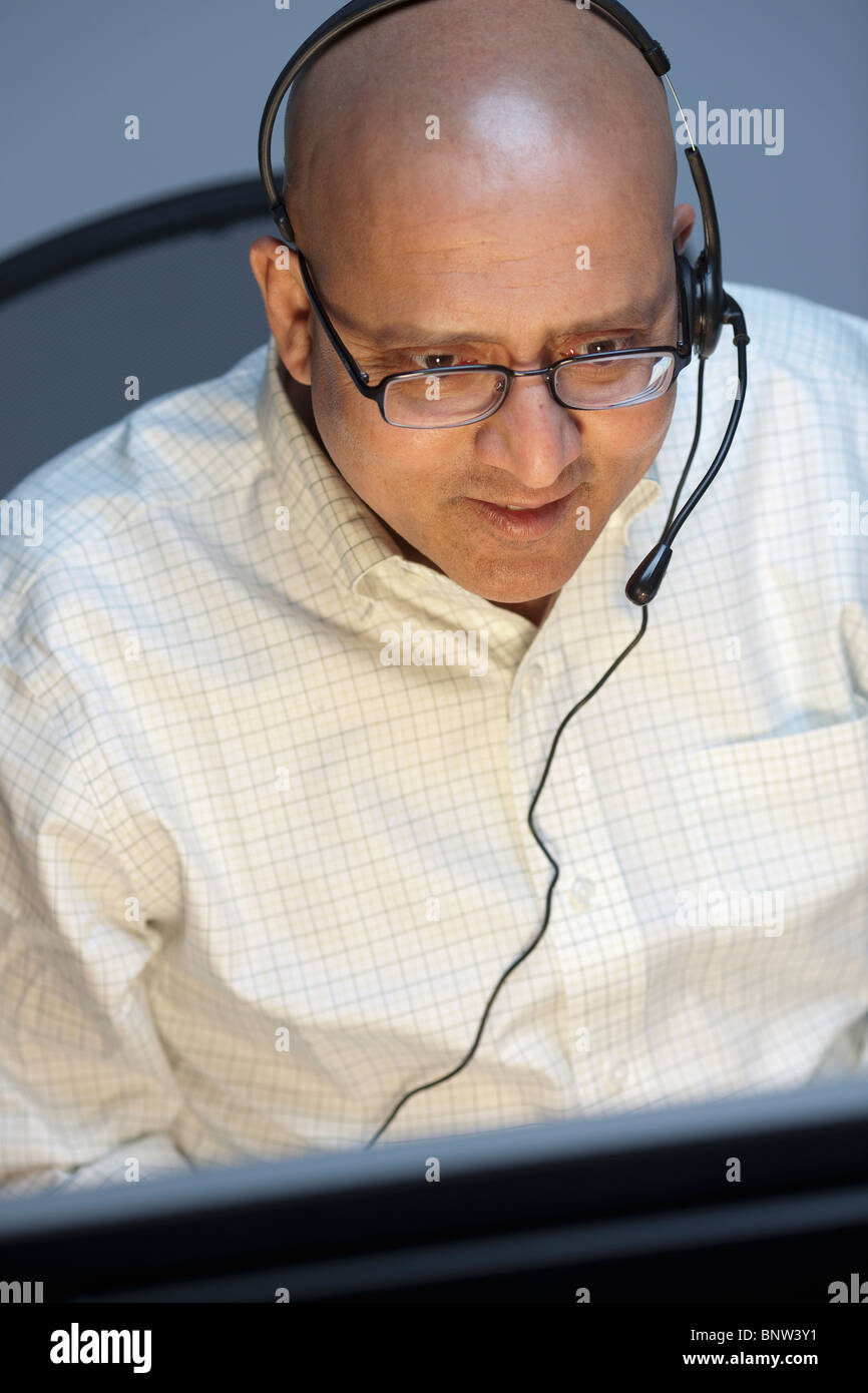 Man wearing headset working on computer Stock Photo - Alamy