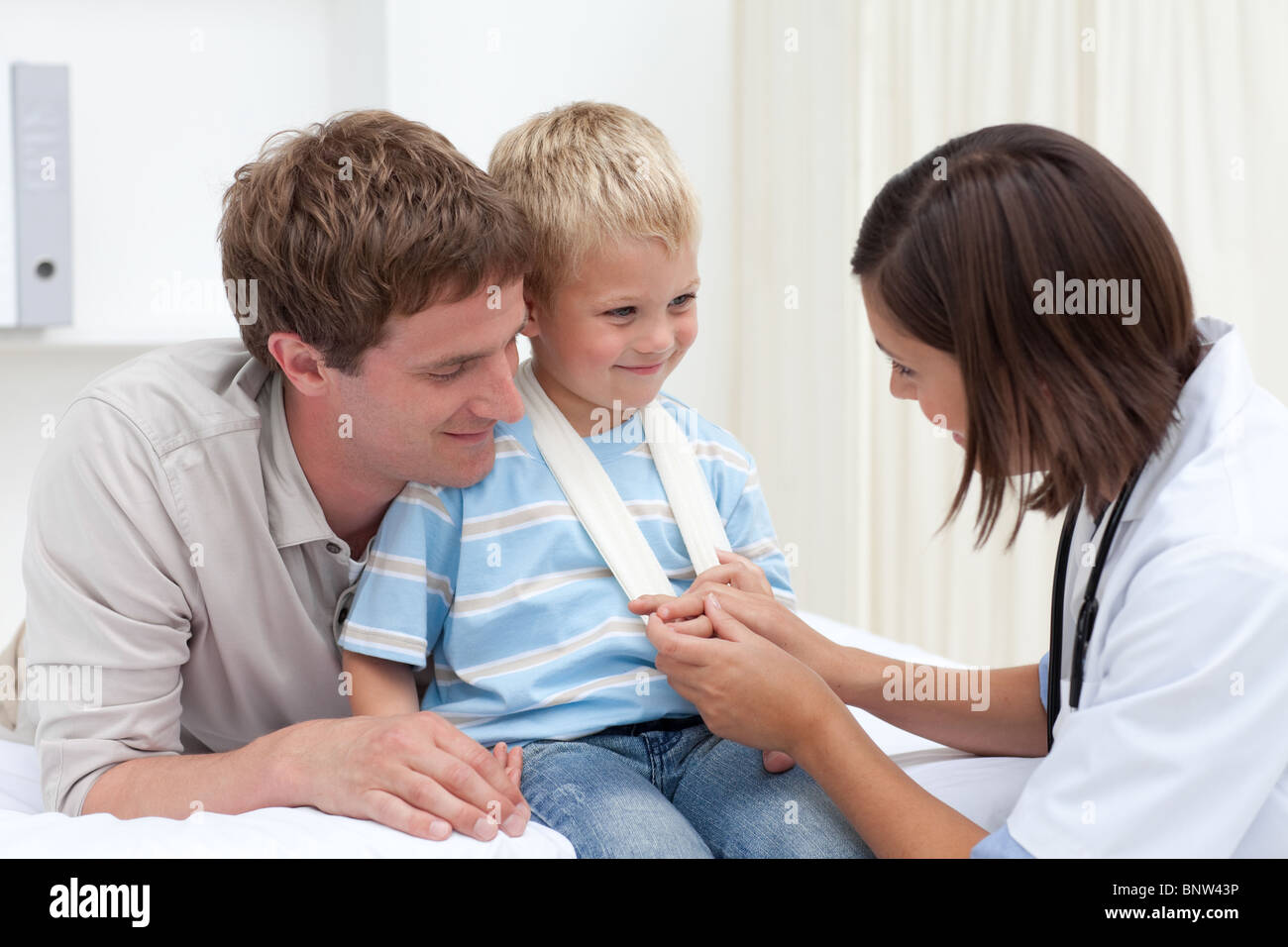 Smiling doctor examining little boy's hand Stock Photo - Alamy