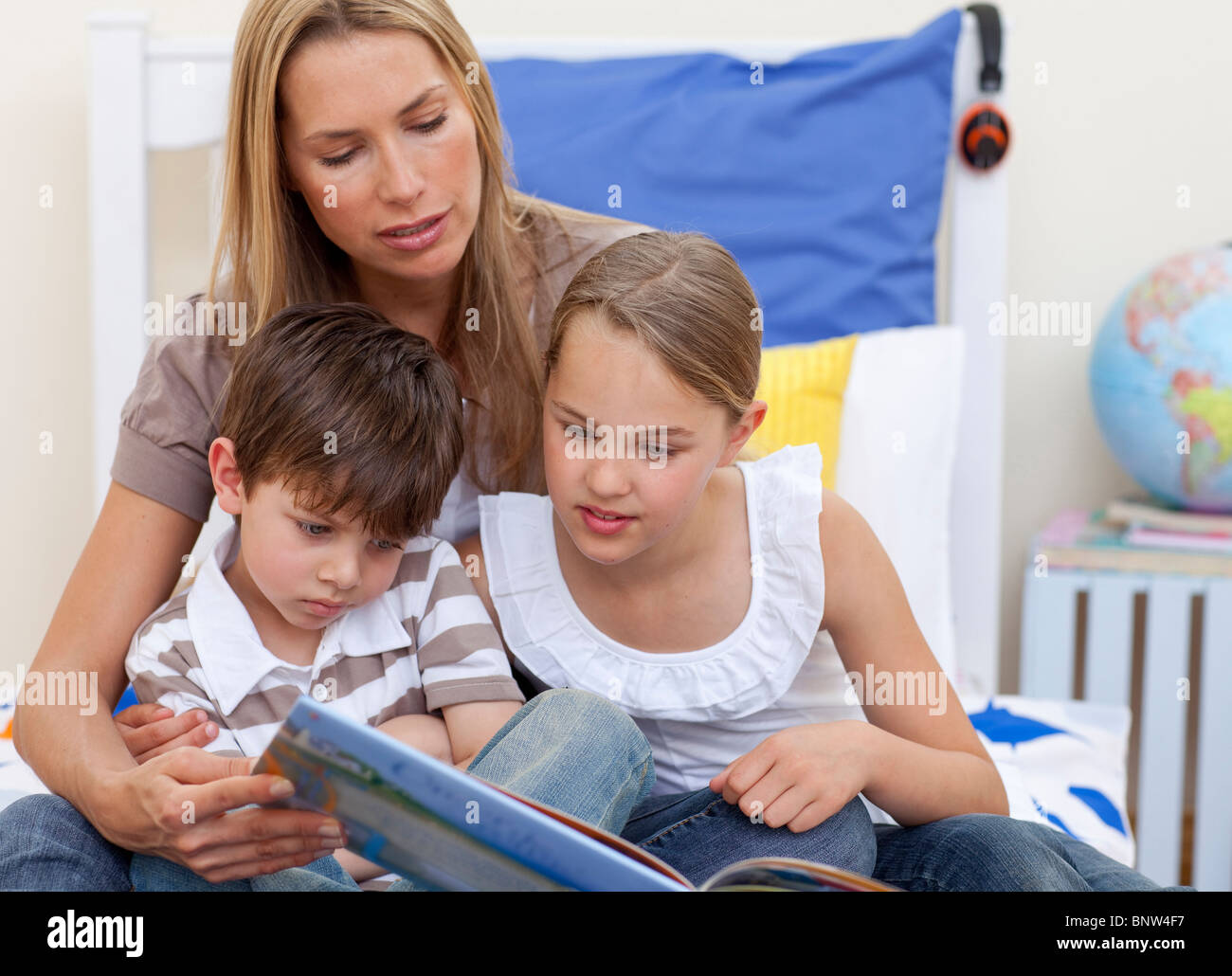 Mother reading a book with her children in bed Stock Photo - Alamy