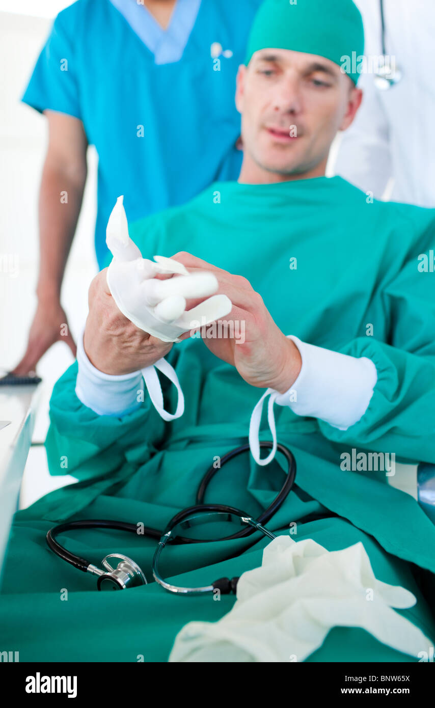 Concentrated surgeon putting on his surgical gloves Stock Photo - Alamy