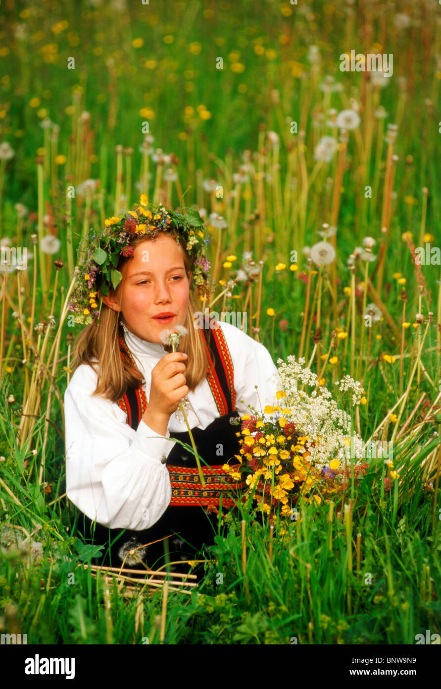 Girl in traditional Midsummer dress picking wildflowers and blowing on ...