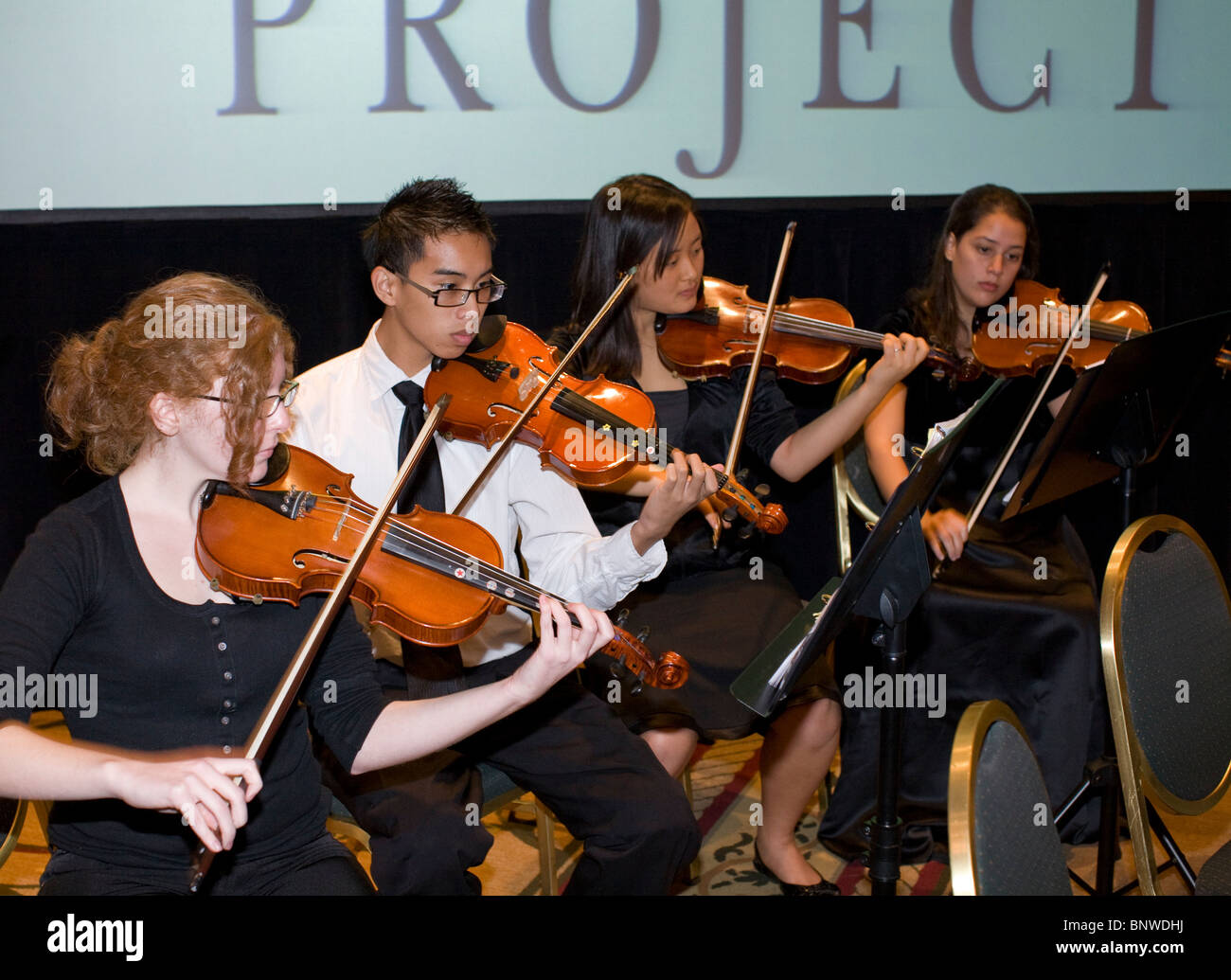 Multi-ethnic high school orchestra ensemble of violinists performs in ...
