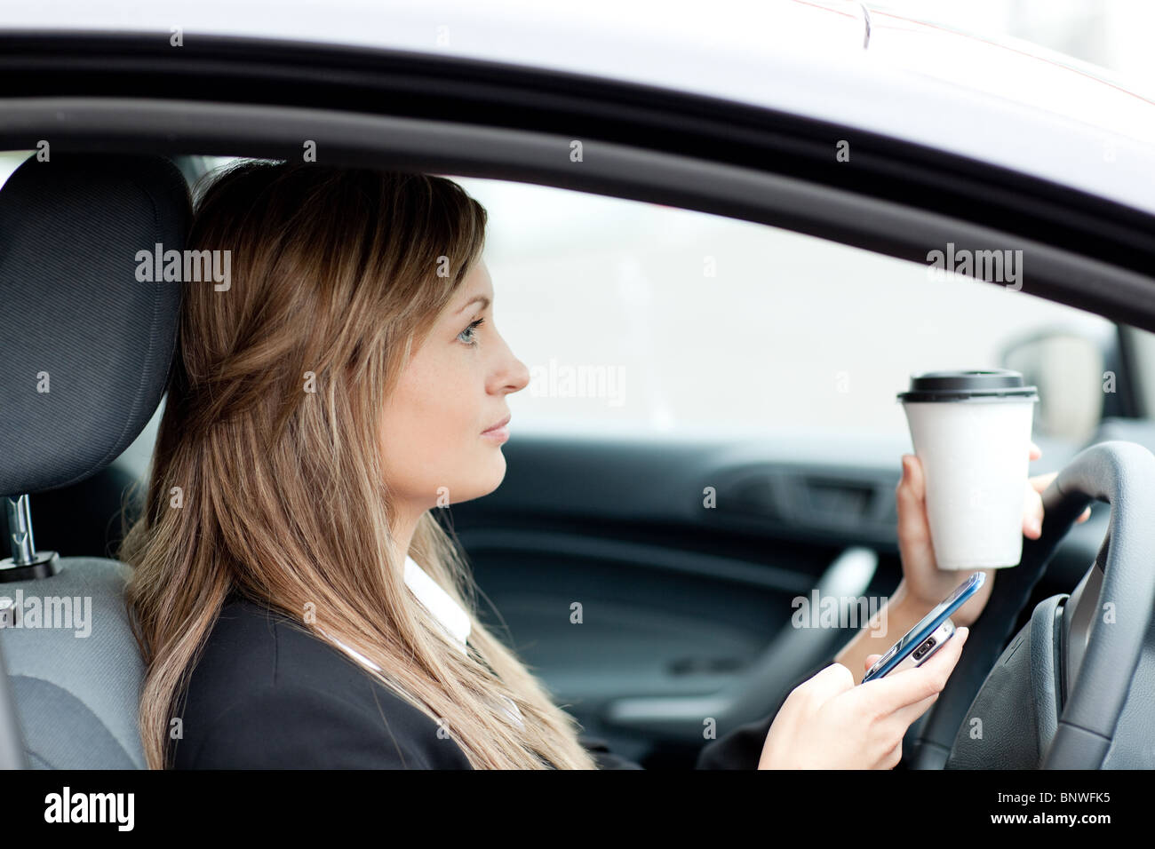 Blond businesswoman sending a text while driving Stock Photo - Alamy
