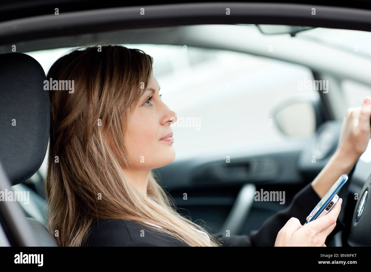 Attractive businesswoman sending a text while driving to work Stock ...