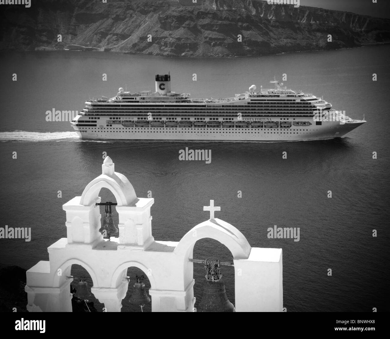 A large cruise ship ts passing by below the town of Oia while leaving ...