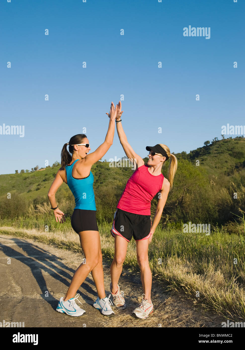 Two trail runners giving each other a high five Stock Photo - Alamy