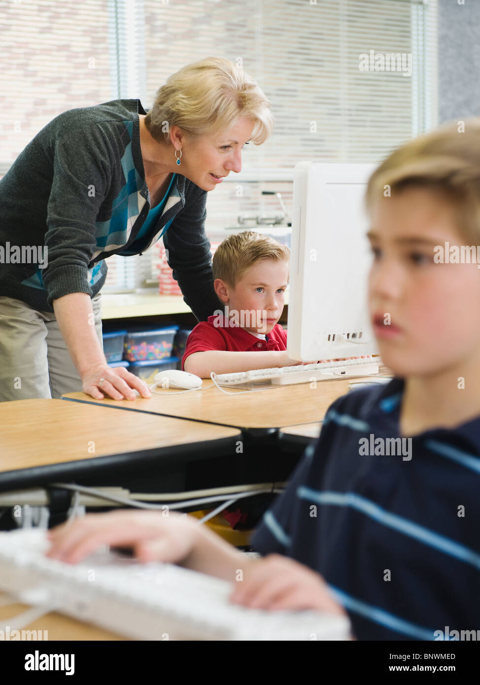 Teacher helping young student in computer lab Stock Photo - Alamy