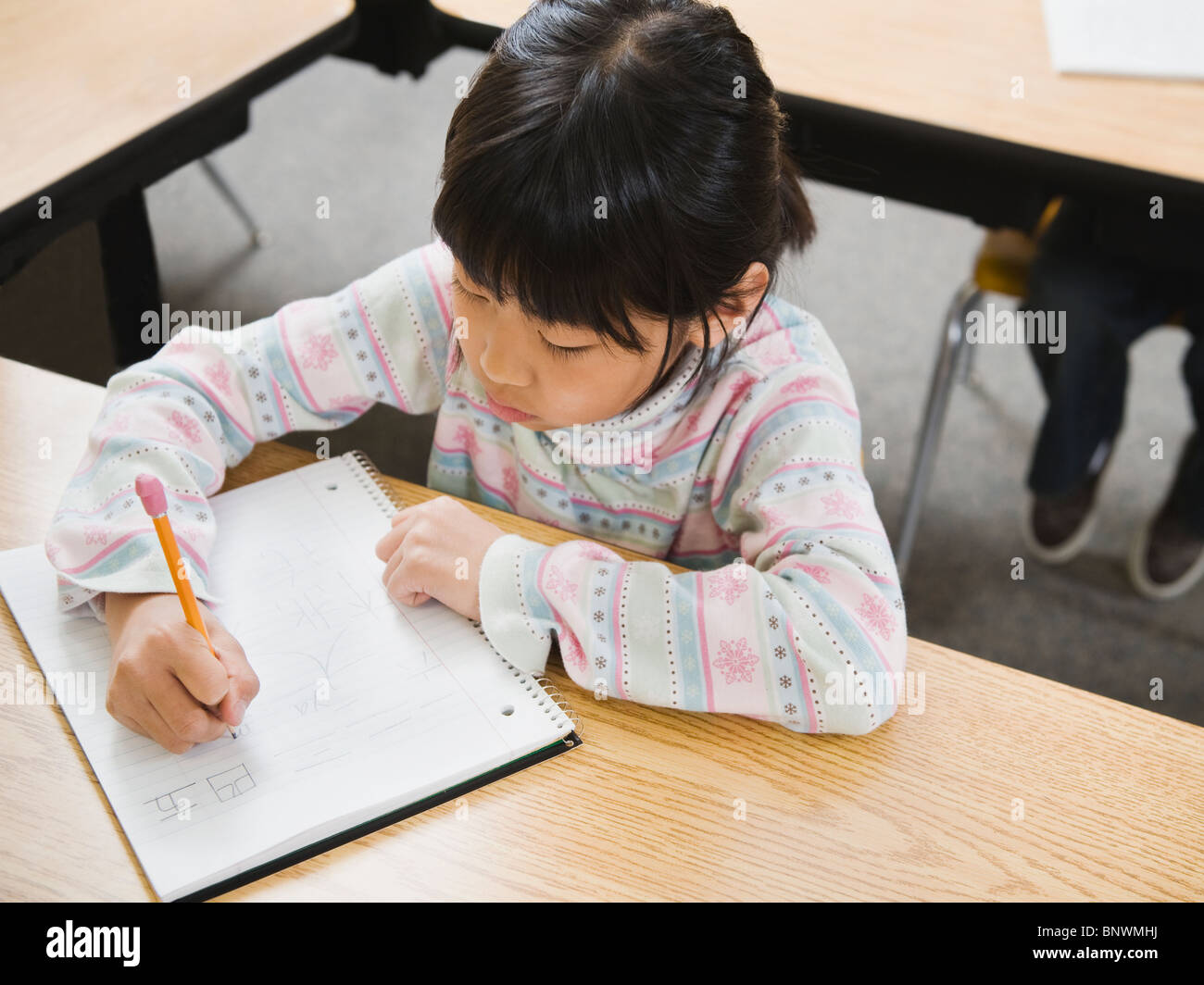Elementary student writing in her notebook Stock Photo - Alamy