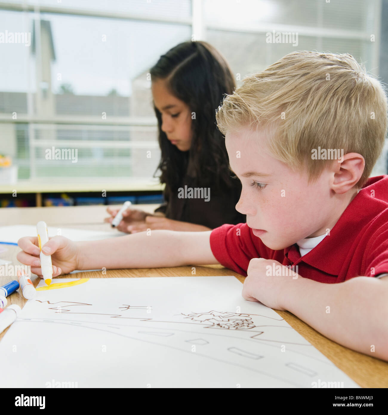 Elementary students drawing at their desks Stock Photo - Alamy