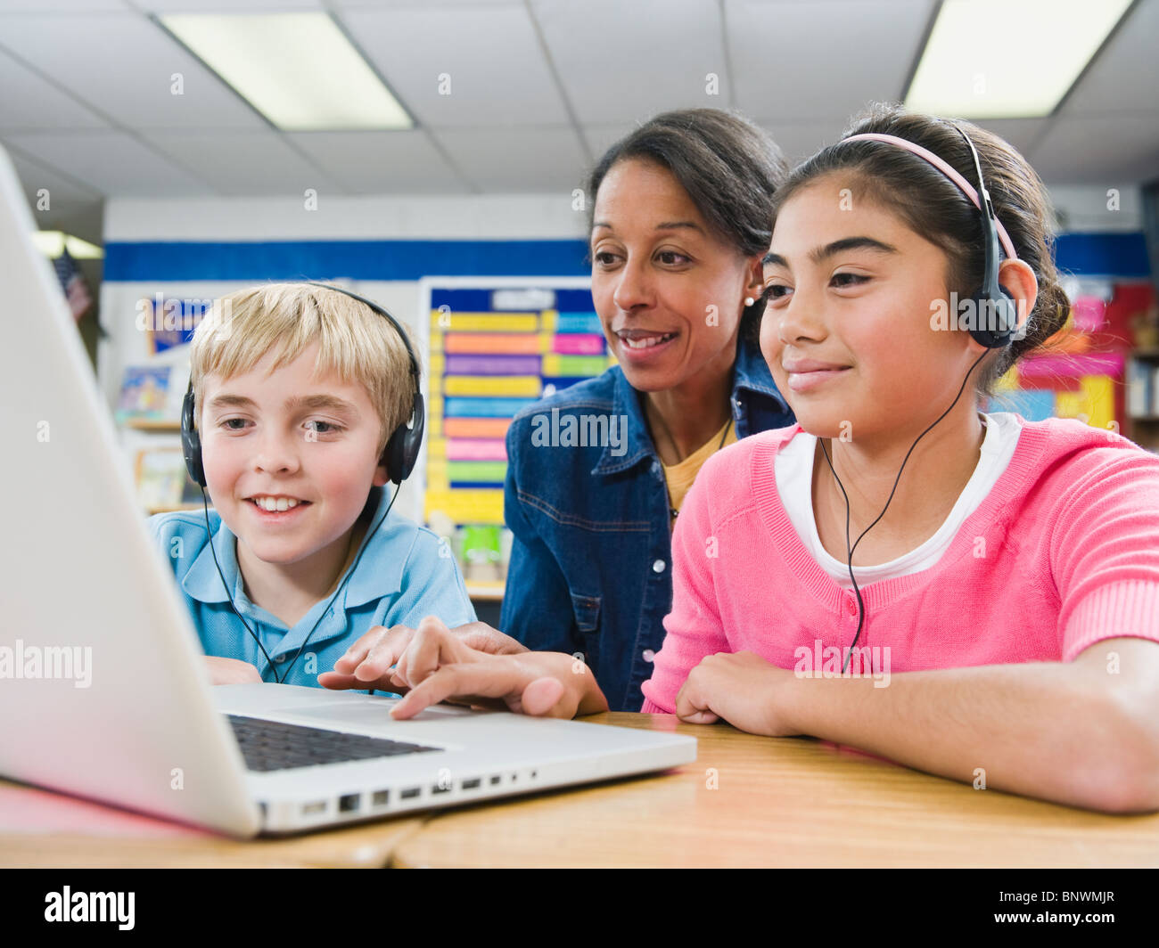 Teacher helping students use laptop Stock Photo - Alamy