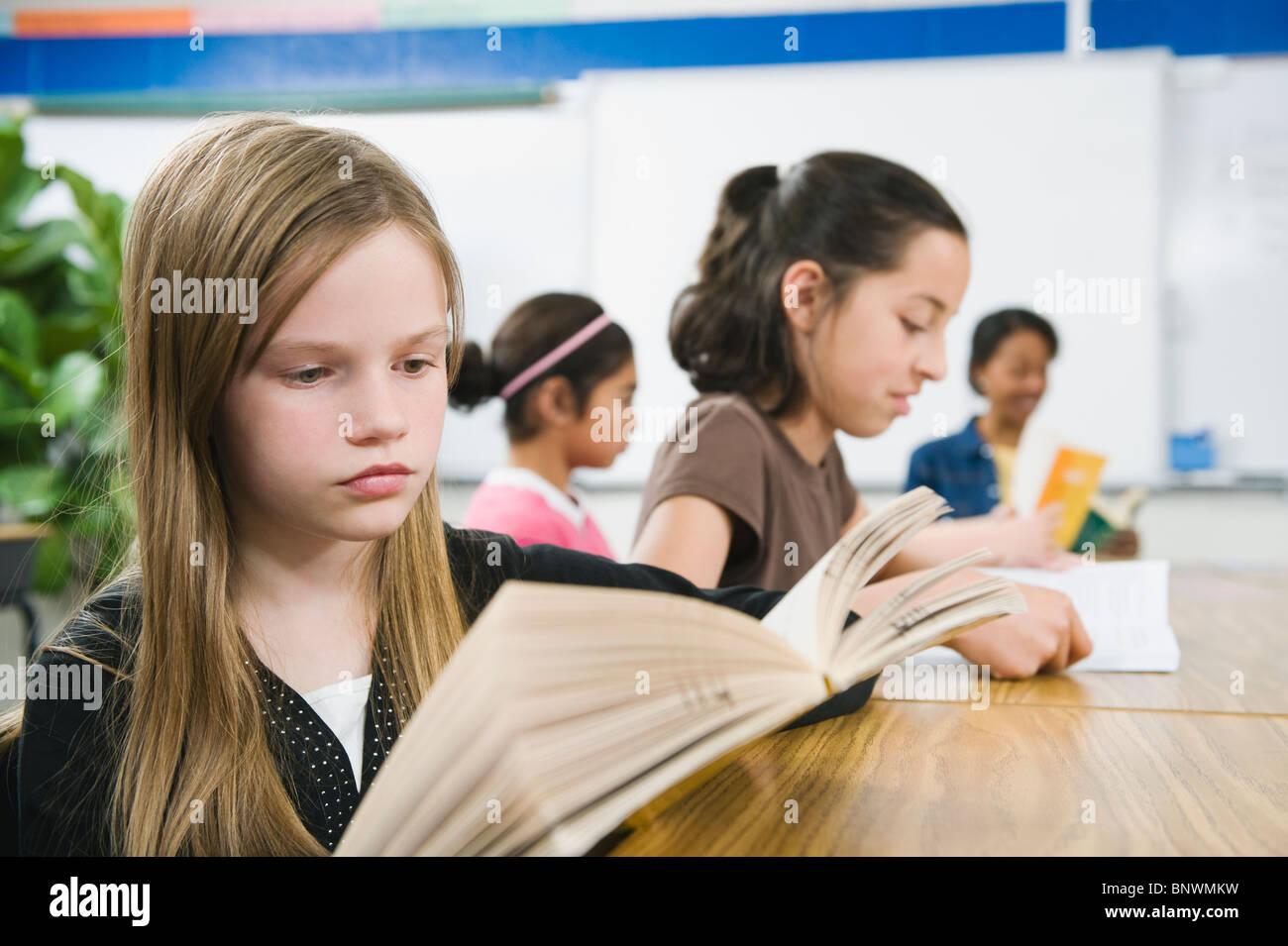 Elementary school students reading books at desk Stock Photo - Alamy