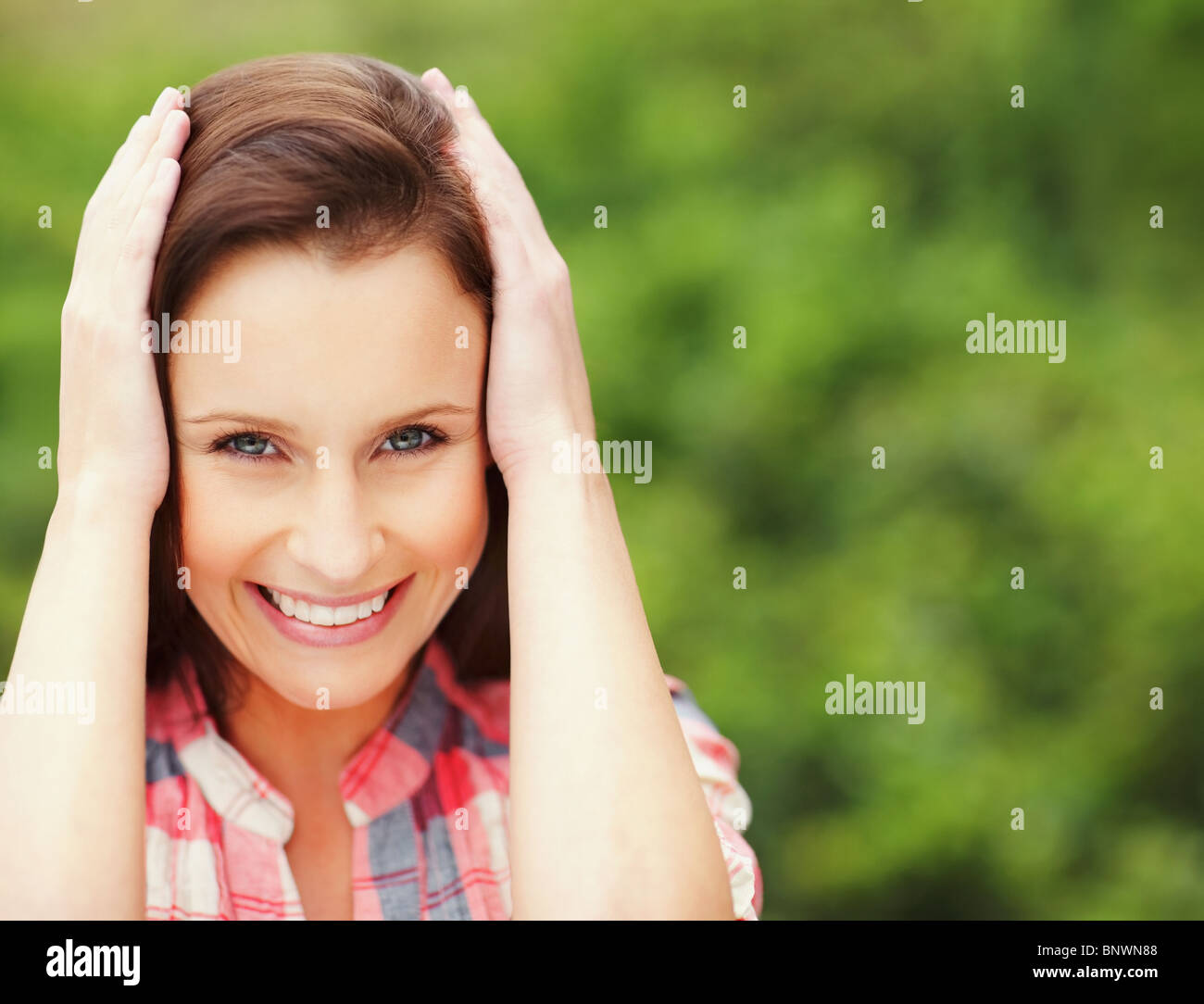 Pretty woman holding her hands against her head Stock Photo - Alamy
